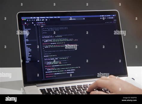 Male Programmer Working On Laptop Computer At White Desk In Office Codding Php Code Stock Photo