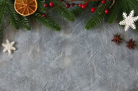 가문비 나무 바늘 빨간 열매 스타 아니스 말린 감귤류 오렌지 과일 조각과 회색 배경에 퐁당 착빙 눈송이의 축제 크리스마스 디자인 포스터 테두리의 이미지 높은 전망 복사 공간