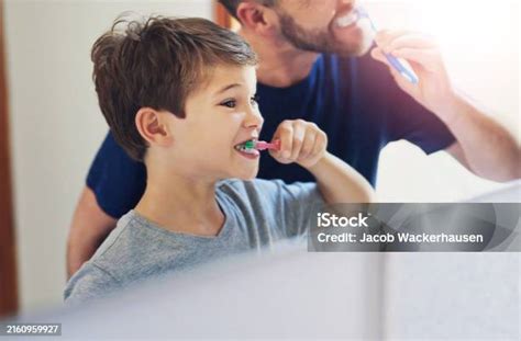 아빠 가족 아이가 집에서 치과 위생 청소 및 지원을 받으며 거울을 보며 양치질을 합니다 욕실에서 치약으로 구강 및 구강 건강을 배우는 소년 또는 어린이가 있는 아버지 남성