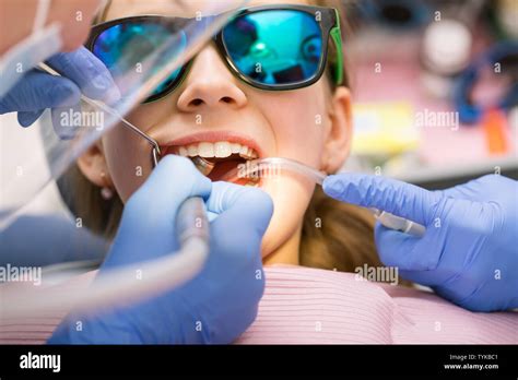 Dentist Performing Dental Filling Procedure To Preteen Girl In