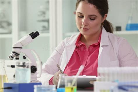 Female Scientist Taking Notes While Reviewing Results Of Scientific
