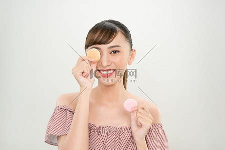 微笑的亚洲女人眼睛上拿着蛋白杏仁饼干高清摄影大图 千库网