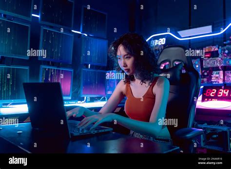 Female Asian Hacker In Hideout Place With Dark Environment And Multiple