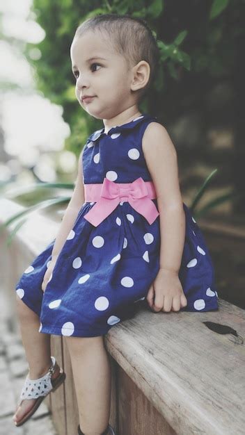 Premium Photo Cute Girl Looking Away While Sitting Outdoors