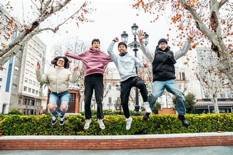 형형색색의 단풍 속에서 함께 뛰어다니는 활기찬 다민족 학생들은 건축을 배경으로 한 도시 공원에서 동지애와 기쁨을 표현합니다 18 19세에 대한 스톡 사진 및 기타 이미지