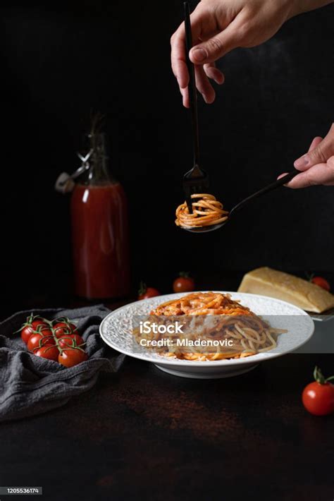토마토 소스와 파마산을 곁들인 파스타 어두운 배경에 파스타와 흰색 접시 포크와 스파게티와 숟가락을 들고 여성의 손 포크에 스파게티 낮은 키 세로 복사 공간 음식에 대한 스톡