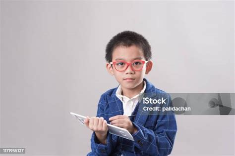회색 배경에 양복을 입은 똑똑한 소년 아시아 소년은 안경을 쓰고 손에 보드에 메모를하고 아이와 교육 개념 가정의 방에 대한 스톡