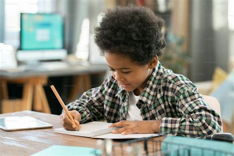 아프리카 민족의 초등학생이 컴퓨터에 대해 거실에서 탁자 옆에서 숙제를 하면서 카피북에 메모를 하고 있다 사진 Unsplash의 아프리카계 미국인 소녀 이미지