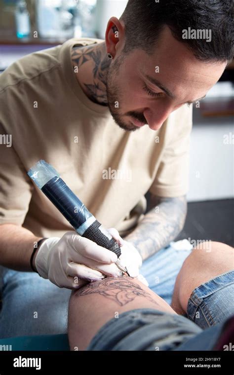 Professional Tattoo Master In Latex Gloves Making Tattoo On Leg Of