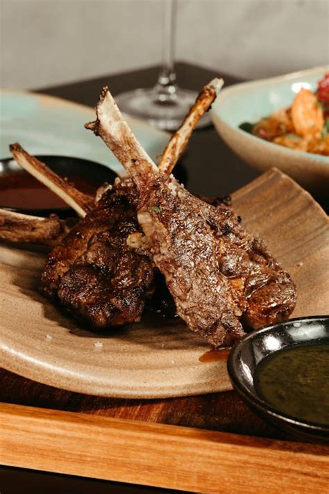 갈색 고기 고명 그릴 다육 단백질 도자기 접시 딥핑 소스 레스토랑 레스토랑 장면 로즈마리 맛있는 맛있는 식사 먹는 목조 테이블 미식가 보르 바