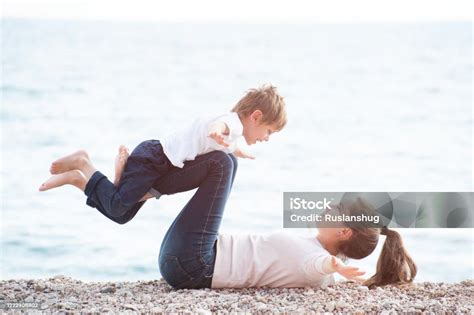 야외 피트니스 운동 중 바다 근처 그녀의 다리에 작은 웃음 아이를 들고 활동적인 어머니 여자의 가족 웰빙 스포츠 라이프 스타일 개념 2명에 대한 스톡 사진 및 기타 이미지