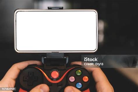 검은 배경에 격리된 손에 스마트폰이 있는 게임 패드 모바일 게임 개념입니다 복사 공간을 위한 스마트폰의 빈 흰색 화면 Brand Name Video Game에 대한 스톡