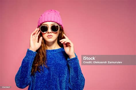 파란색 스웨터와 분홍색 모자를 입고 포즈를 취한 현대 의 젊은 여성 재미있는 표정을 만들기 개성 개념에 대한 스톡 사진 및 기타 이미지 Istock