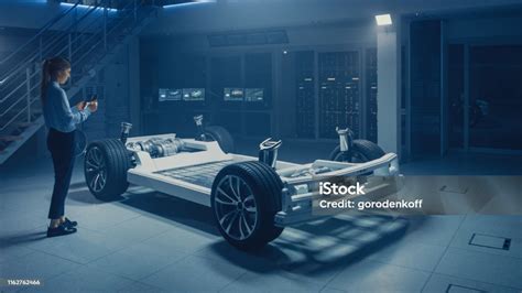 3d Cad 소프트웨어 모델링을 통해 태블릿 컴퓨터 증강 현실을 사용하여 전기 자동차 섀시 플랫폼에서 작업하는 자동차 엔지니어 혁신적인 시설 바퀴 엔진 배터리가있는 차량