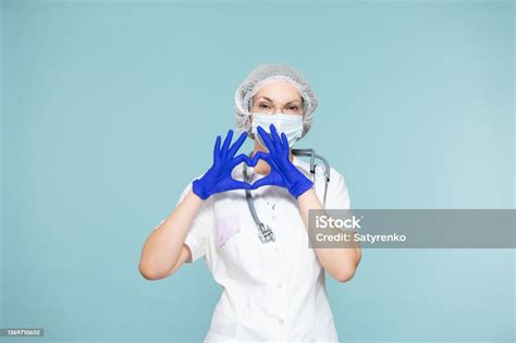 심장 상징 사랑 청진기와 개인 보호 복을 입은 의사 또는 간호사 여성 파란색 배경에 마스크 장갑 고글 모자 붙여넣기를 복사합니다