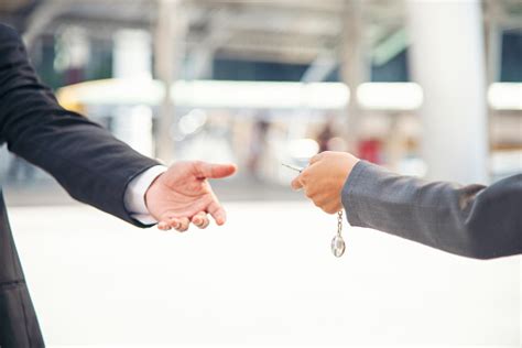 여성 손은 남자 렌터카 서비스에 원격 제어 자동차 키를 제공합니다 남자에게 새 차 열쇠를 보여주는 젊은 여자의 손을 감싼다