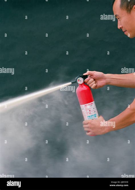 Asian man using fire extinguisher Stock Photo - Alamy