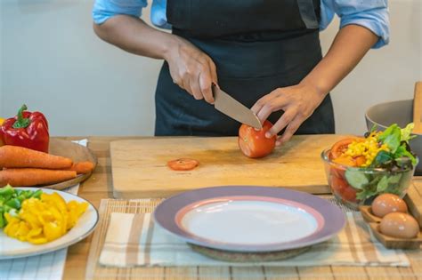 Mano De Chef De Primer Plano Cortar El Tomate En La Tabla De Cortar En La Cocina Moderna Foto