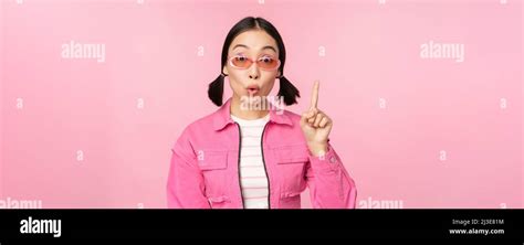 Cool And Stylish Asian Girl Raising Finger Pointing Up Suggesting Smth Pitching An Idea Or