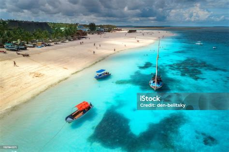화창한 날에 모래 해변과 열대 바다 해안에 보트의 공중 보기 인도양 잔지바르 아프리카의 여름 휴가 보트 야자수 투명 한 푸른 물
