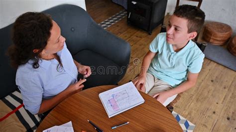 Mother Helping Son With Homework At Home Focusing On Creativity And