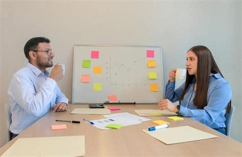 Premium Photo A Man And Woman Sitting At A Table With A White Board And Sticky Notes