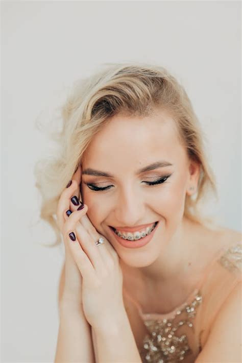 감정 개인 관리 광점 교정기를 한 여성 금발 긍정적인 기쁨 눈을 감다 라이프스타일 매니큐어 메이크업 모델 미소 미소 짓는 바지 멜빵 보석 상쾌한