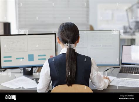 Back View Of Woman Working As Female Engineer Using Computer With