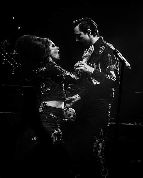 A Man And Woman Standing Next To Each Other In Front Of A Microphone On Stage