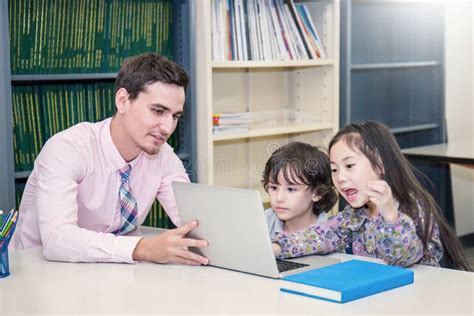 Pupils Studying With Teacher Using Computer Device In Classroom Stock