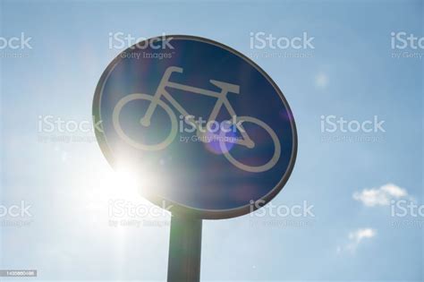 파란색 배경에 흰색 자전거를 묘사한 둥근 도로 표지판은 푸른 하늘 배경에 대한 자전거 타는 사람을 위한 필수 자전거 경로를