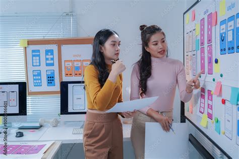 two female ui ux designers are discussing over mobile app interface
