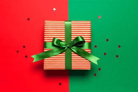 녹색 리본과 홀로그램 반짝이 색종이 붉은 녹색 배경 상단보기에있는 별의 색종이 모양의 선물 상자는 텍스트를위한 공간을 평평하게