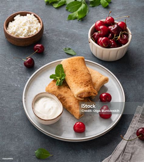 맛있는 수제 팬케이크 또는 코티지 치즈가 들어간 크레페와 어두운 배경에 사워 크림이 든 접시에 신선한 체리 갈색에 대한 스톡