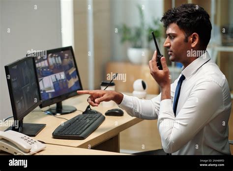 Security Guard Communicating To Coworkers Via Walkie Talkie When