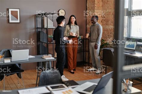 로프트 오피스 룸에서 함께 서서 커피를 마시는 세 명의 다민족 동료의 수평 긴 샷 18 19세에 대한 스톡 사진 및 기타 이미지 18 19세 20 24세 가정 생활