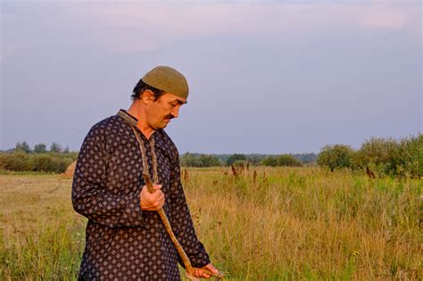 두개골 모자와 전통적인 옷을 입은 한 고위 무슬림 남성이 건초밭에서 손으로 낫 잔디를 깍는다 55 59세에 대한 스톡 사진 및 기타 이미지 Istock