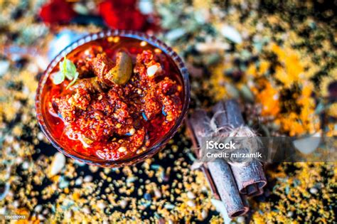 인기 있는 인도 파랑 유리 그릇에 있는 망고의 채소 절 임 즉 유리 그릇 이나 케리 카 Achar에 향신료와 망고를 포함 한 전체 원료와 함께 검은 색 빛나는 표면에 강황에