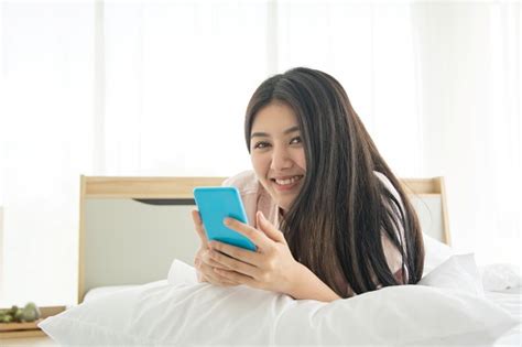 분홍색 잠 옷에 있는 웃는 여자의 초상화 휴대 전화에서 정보 보기 침대에 아침 빛을 환영 합니다 귀여운에 대한 스톡 사진 및 기타 이미지 Istock