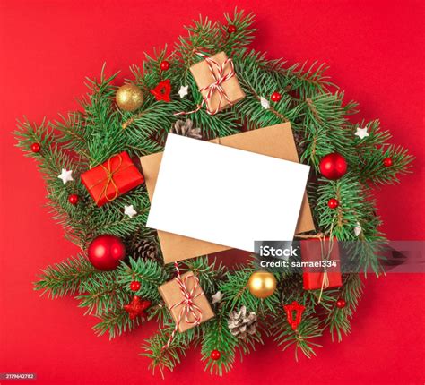 빨간 배경에 솔방울 전나무 가지 선물 상자 축제 장식 및 솔방울로 만든 크리스마스 화환에 빈 인사말 카드 플랫 레이 모형 새해 복 많이 받으시고 겨울방학 초대장 선물 상자에