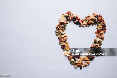 다양한 종류의 건강에 좋은 곡물과 말린 과일이 흰색 배경에 텍스트나 이미지를 위한 빈 공간이 있는 하트 모양으로 배열되어 있습니다 건강한 음식과 체중 감량 건강한 간식