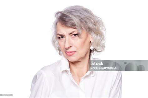 주름잘 돌보는 얼굴을 가진 불쾌한 은퇴 한 노인은 흰색 배경 위에 고립 된 카메라를 의심스럽게 보고 실망한 것처럼 보입니다 사람 얼굴에 대한 스톡 사진 및 기타 이미지