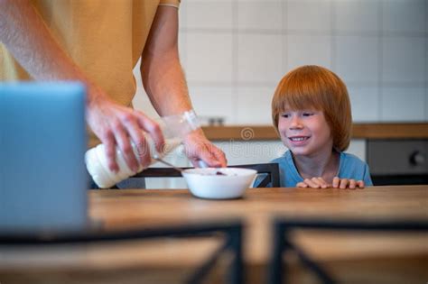 Hombre Vertiendo Leche En El Plato De Su Hijo Foto De Archivo Imagen
