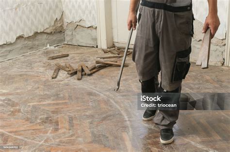 주택 개선 건설 노동자 또는 핸디맨은 까마귀 막대 도구를 사용하여 오래된 나무 쪽모이 세공 마루 바닥을 제거하고 있습니다 오래된 나무 바닥 개조 Diy에 대한 스톡 사진 및