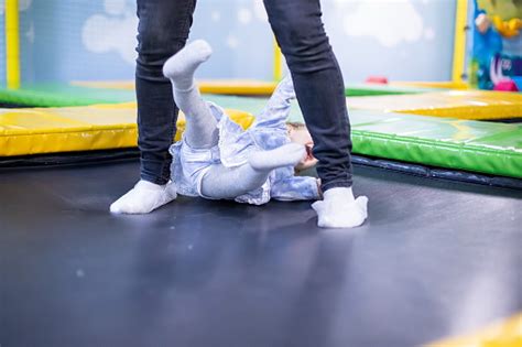 부모와 함께 트램폴린에 점프하고 웃고 있는 드레스를 입은 귀여운 유아 소녀 어린이 놀이 센터의 어린이 놀이터에서 흐린 배경 18 23 개월에 대한 스톡 사진 및 기타 이미지