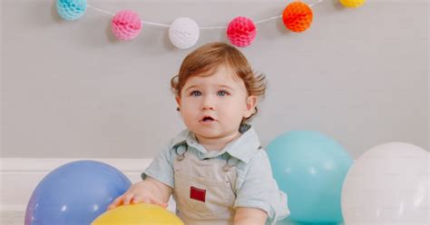 그의 첫 번째 생일을 축하하는 재미있는 백인 아기 아이 아이 유아는 화려한 풍선으로 바닥에 앉아 있습니다 집에서 실내에서 이벤트 또는 파티를 축하합니다 생일 축하