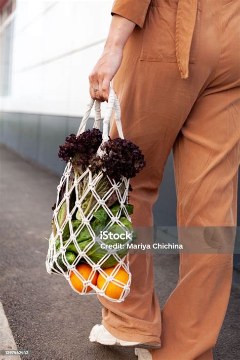 소녀는 비닐 봉지없이 야채 채소와 메쉬 쇼핑 백을 들고있다 제로 폐기물 플라스틱 무료 환경 친화적 인 개념 수제 마크라메 백 지속 가능한 라이프 스타일 가방에 대한 스톡