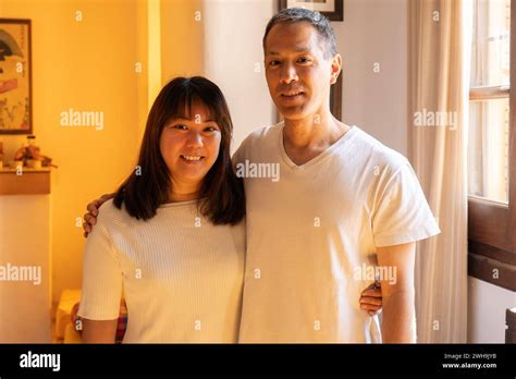 Adult Siblings Standing Hugging Each Other Of Japanese Ethnicity Smiling And Looking At The