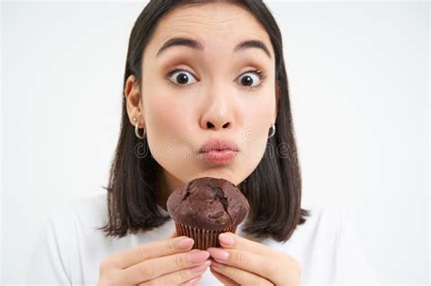 Close Up Of Cute Smiling Asian Woman Holding Chocolate Cupcake Near Mouth Having Bite Enjoys
