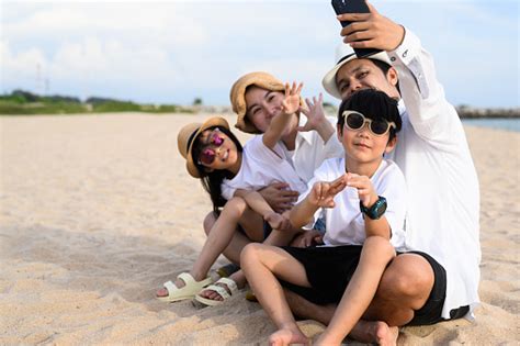 해변에서 셀카를 찍는 행복한 아시아 가족 해변 여행에서 함께 즐거운 시간을 보내는 가족 해변 휴가 중인 가족 자유와 여행 개념 4 명에 대한 스톡 사진 및 기타 이미지